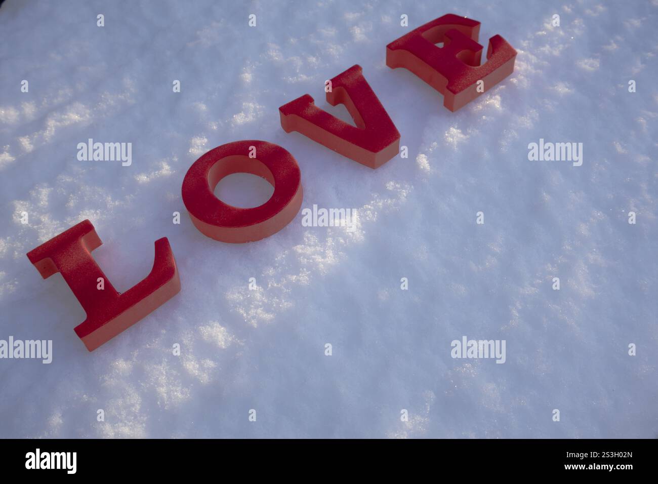The word love in red on the snow with sunlight spots. White background ...
