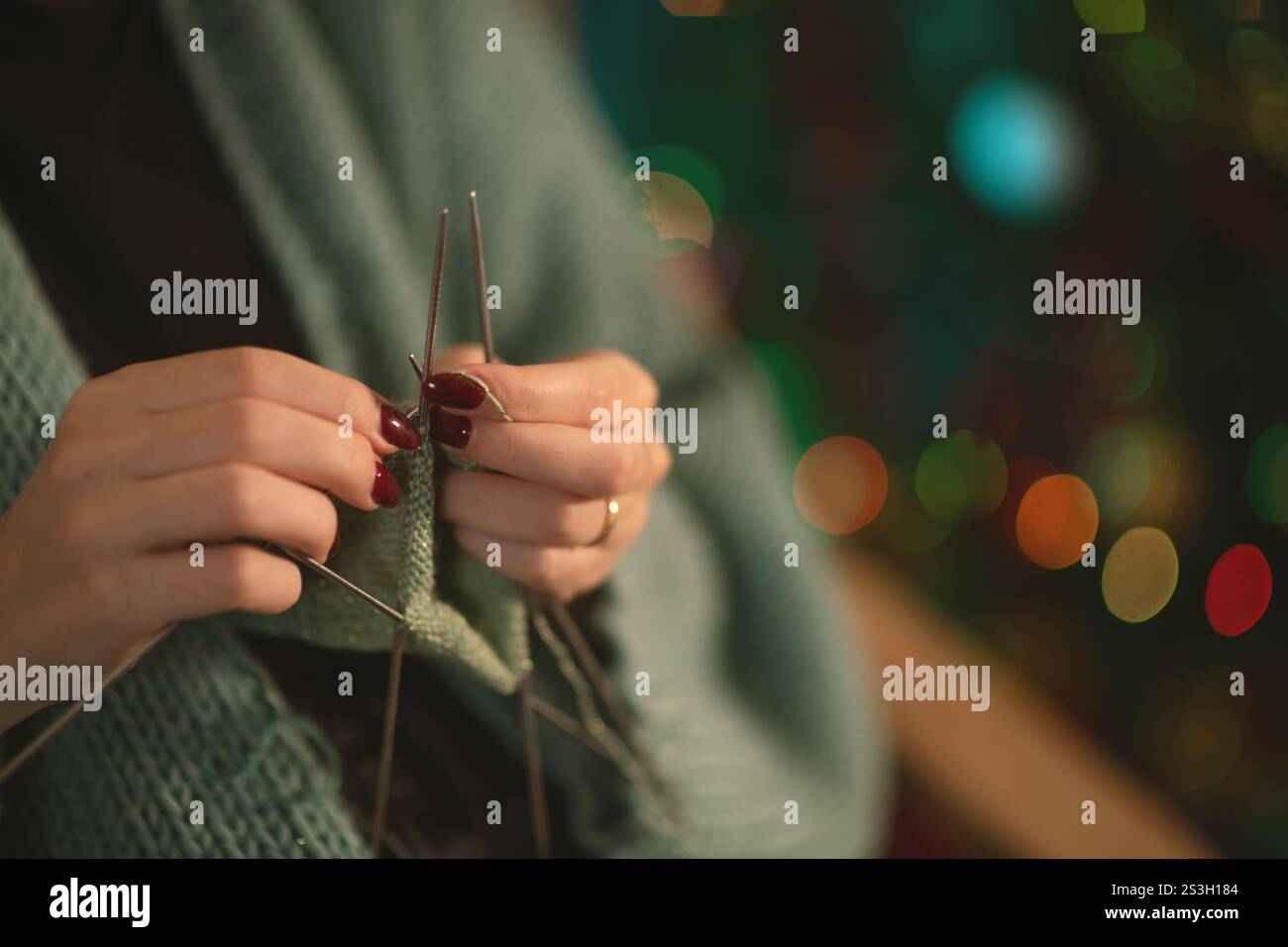 A detailed view of a young woman's hands carefully knitting with green ...
