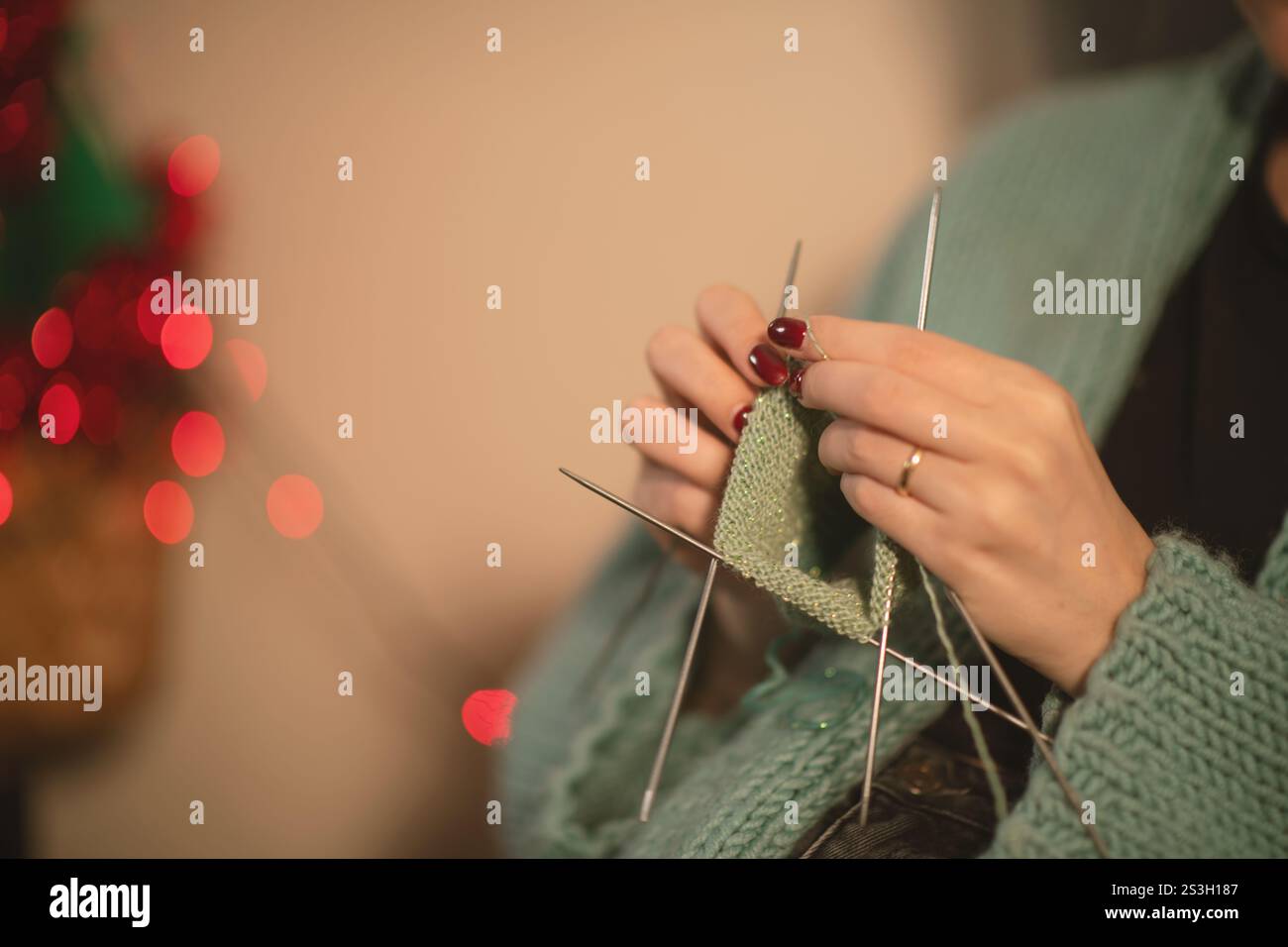 A detailed view of a young woman's hands carefully knitting with green ...