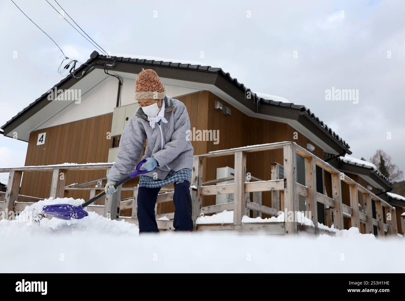A woman removes snow at a temporary house area in Wajima City, Ishikawa ...