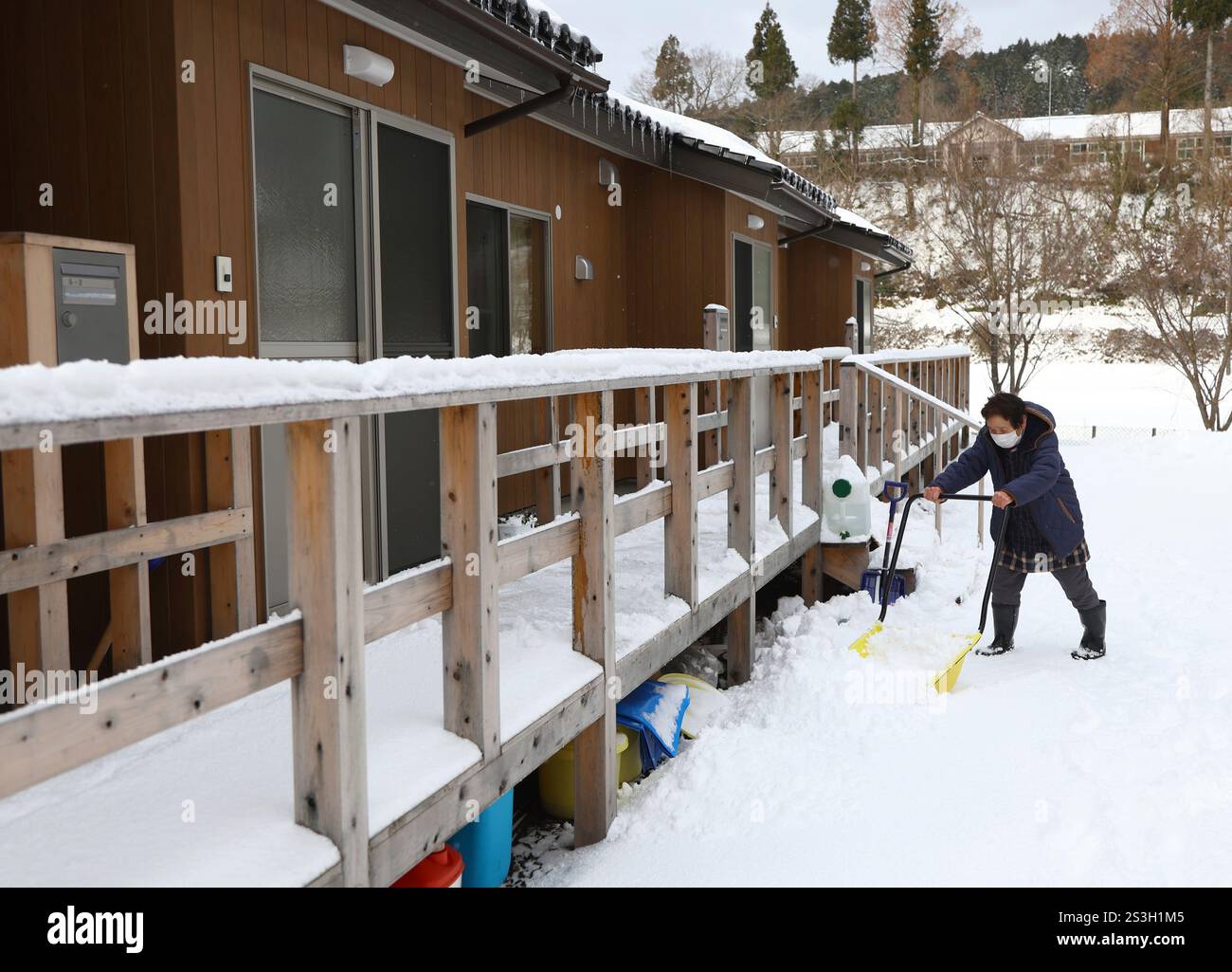 A woman removes snow at a temporary house area in Wajima City, Ishikawa ...