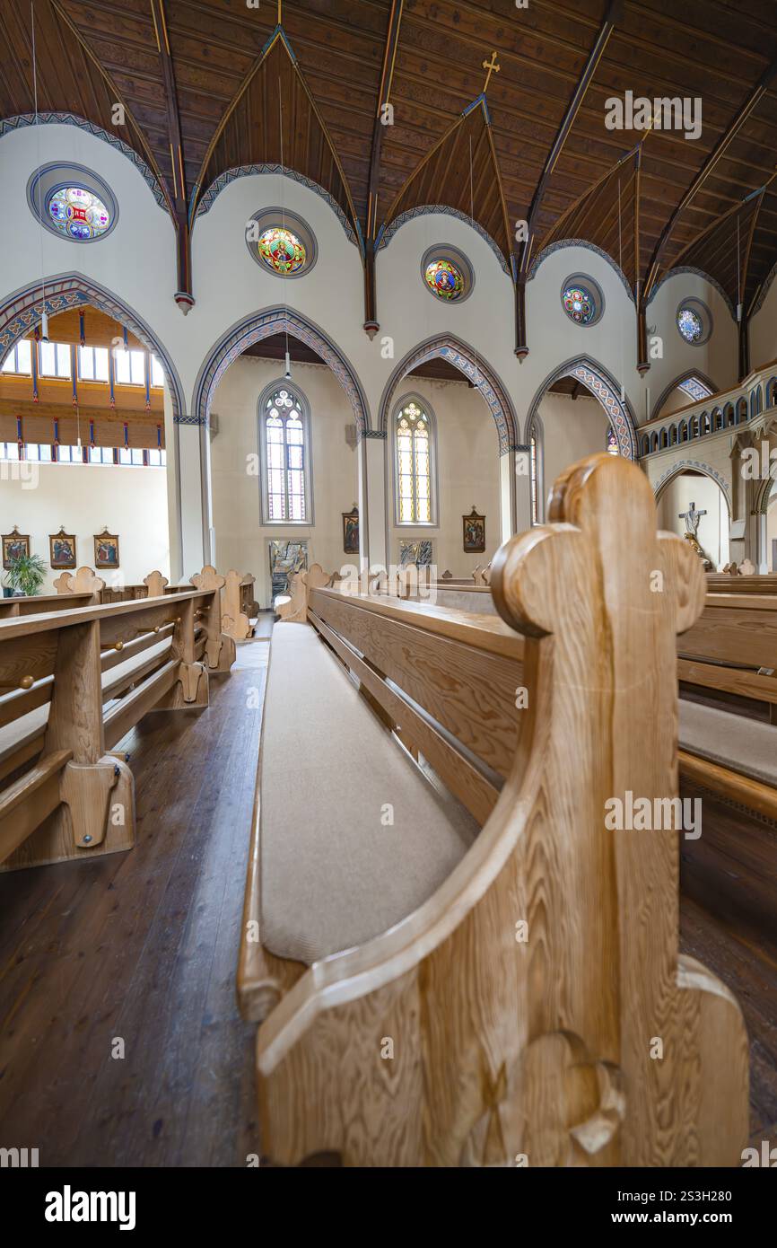 Interior view of a church with wooden benches and stained glass windows ...