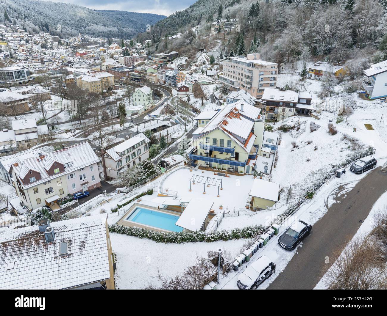 A snowy winter landscape with a view of colourful houses and a pool ...