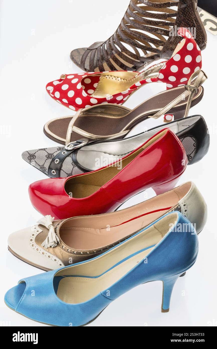 Different coloured shoes with high heels in front of a white background ...