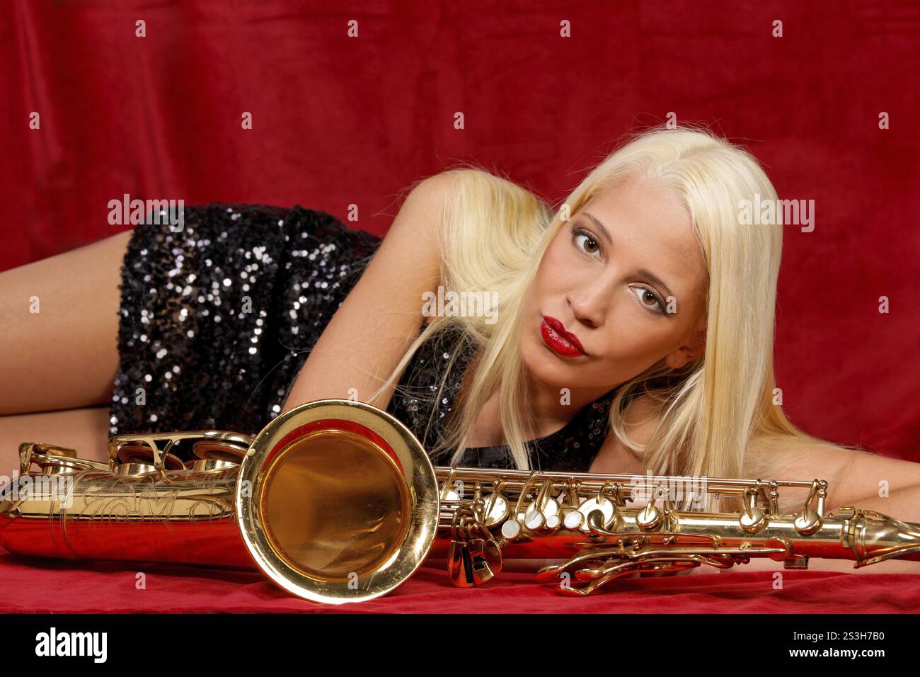 Young pretty musician lies behind her saxophone Stock Photo - Alamy