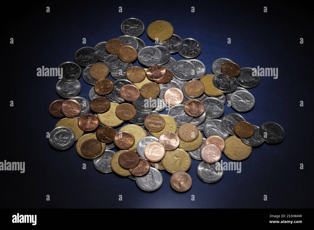 Pile of Canadian coins illuminated on dark blue background Stock Photo ...