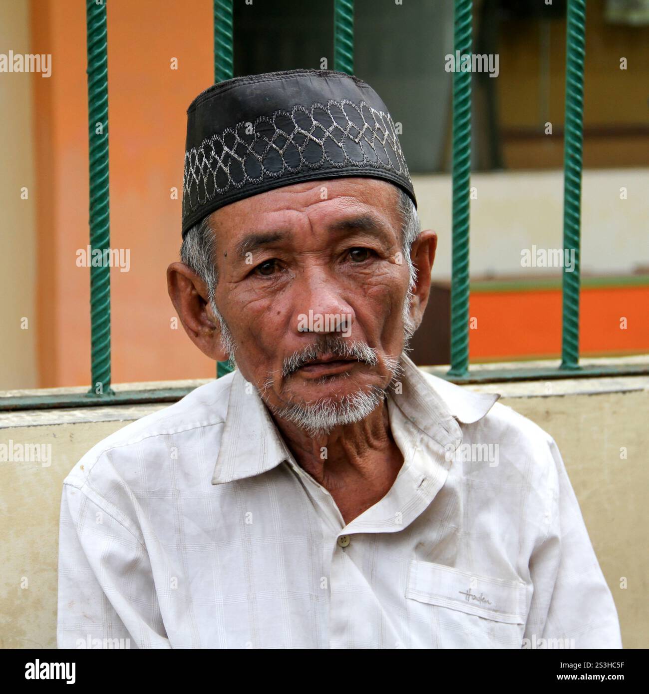 An elderly Minangkabau Indonesian man with a goatee wearing a peci or ...