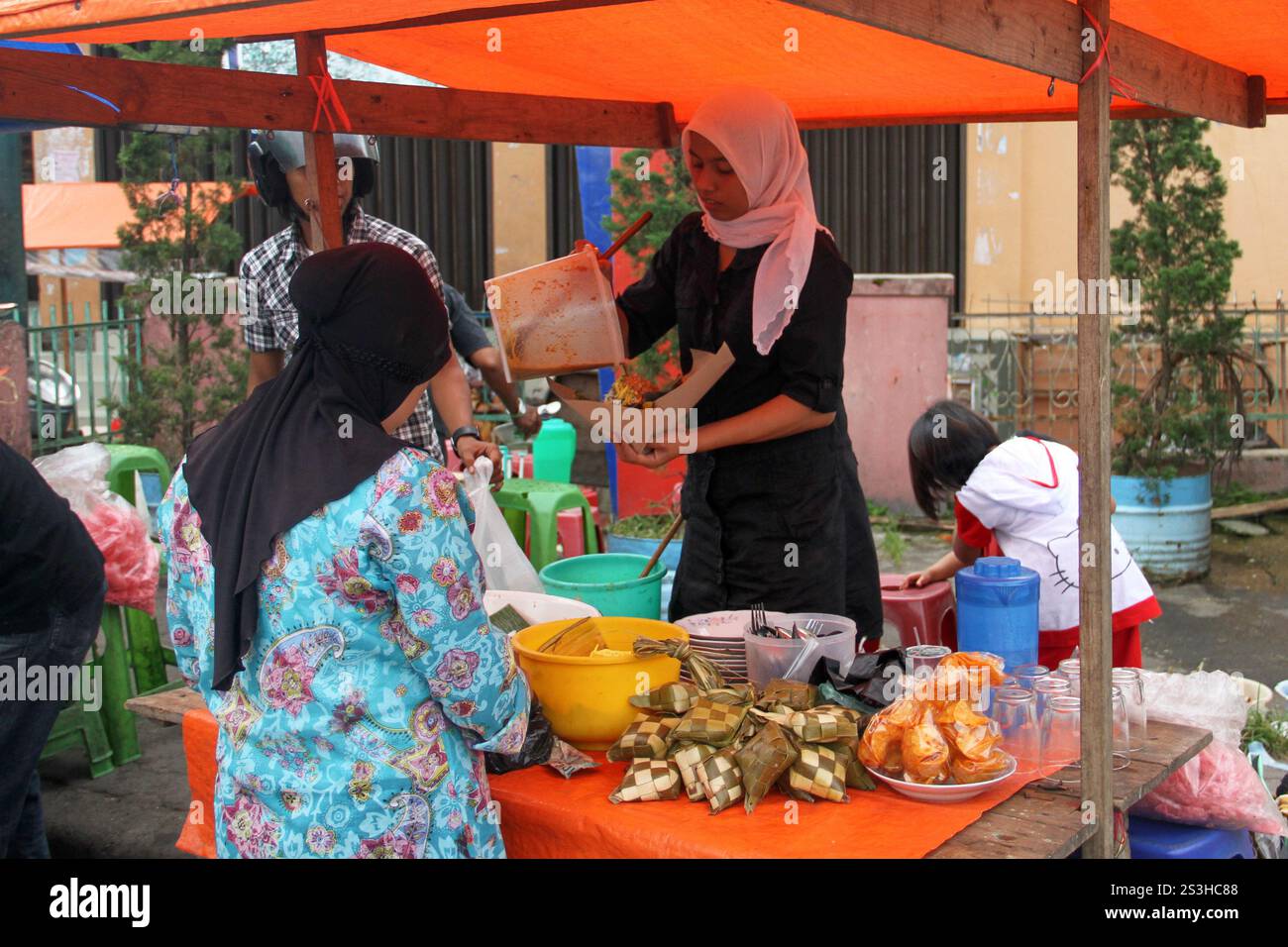 A female Muslim woman selling Indonesian food in a market in ...