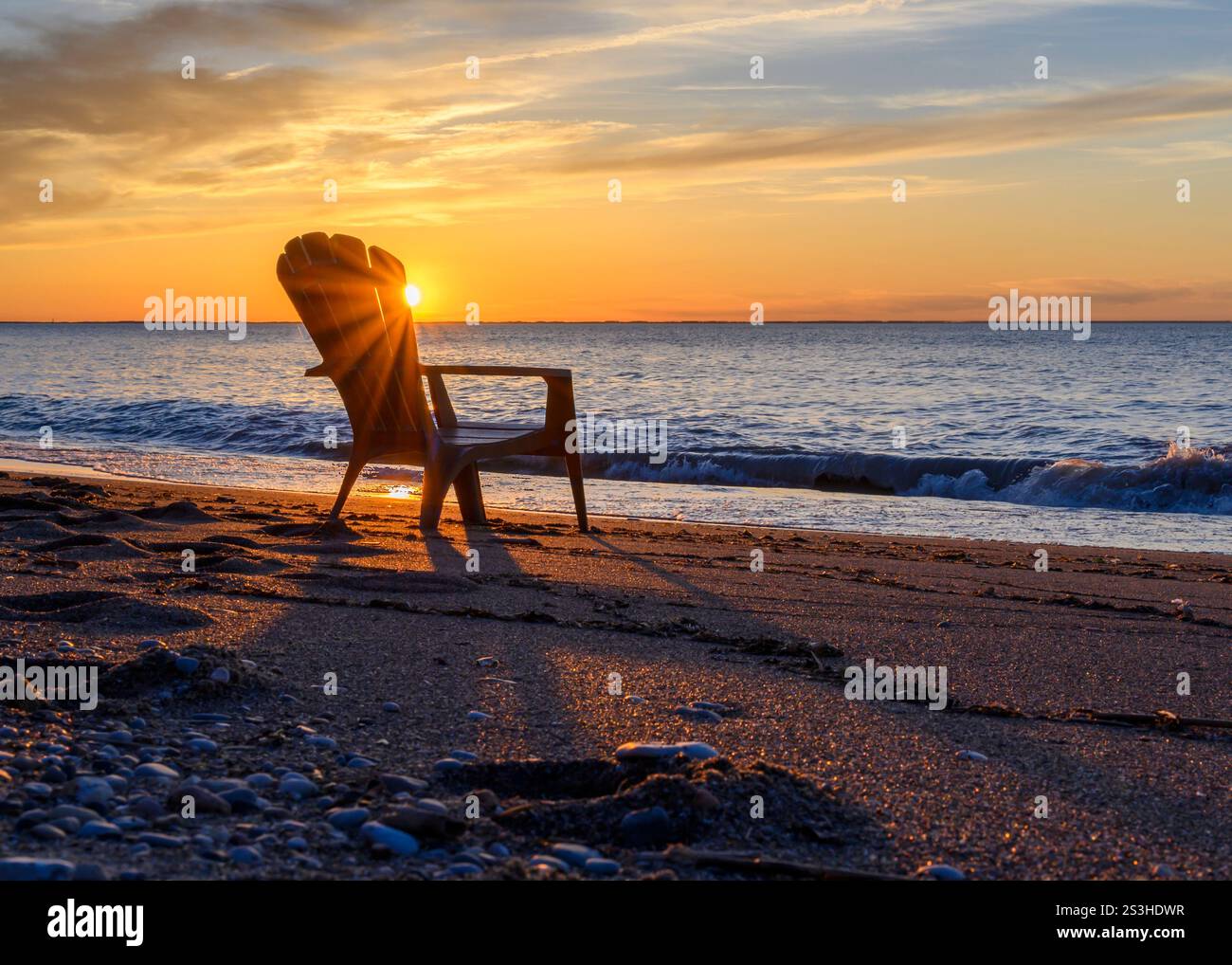 Lake Huron sunset frames an Adirondack chair on the beach, showcasing ...