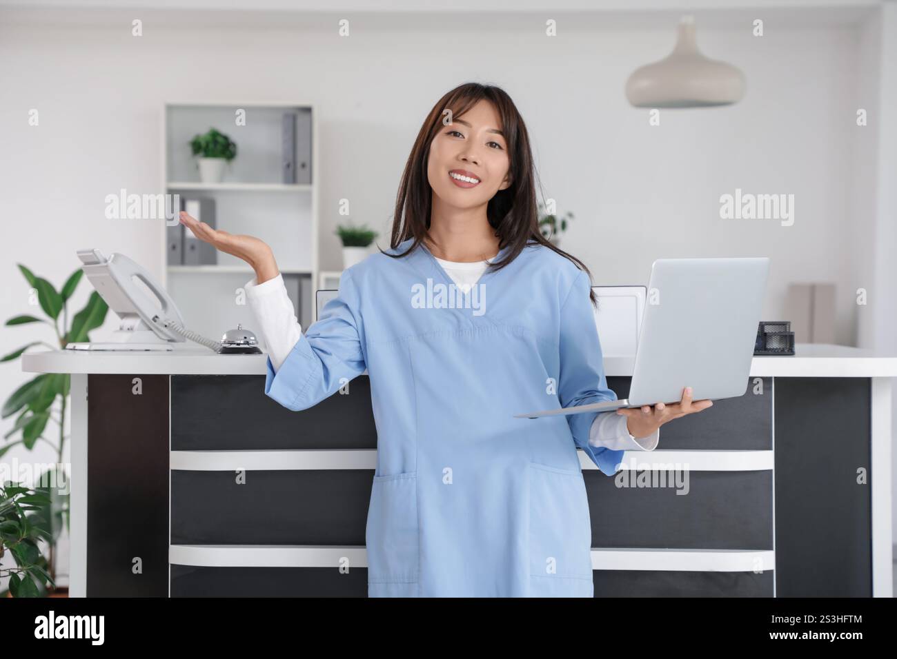 Female Asian medical intern with laptop near reception in clinic Stock ...