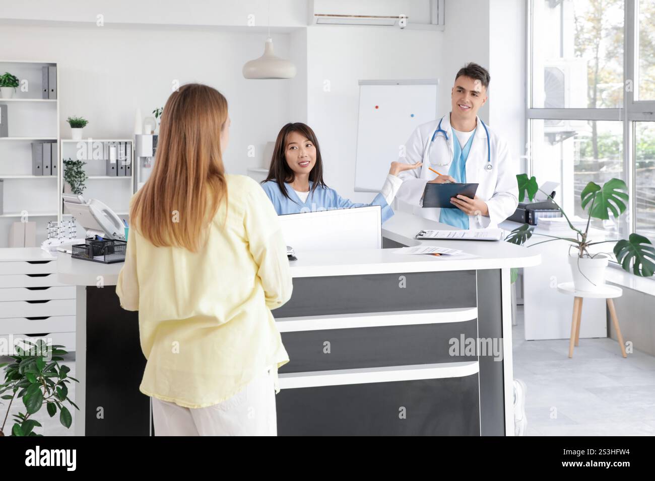 Medical intern working with patient and doctor at reception in clinic ...
