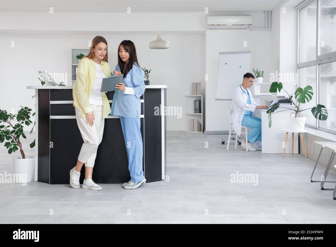 Female Asian medical intern working with patient near reception in ...
