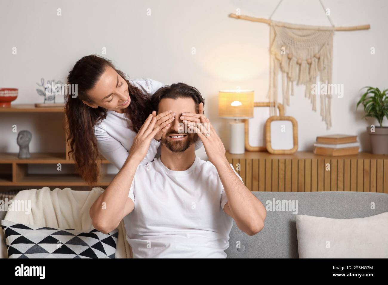 Happy wife covering her husband's eyes at home Stock Photo - Alamy