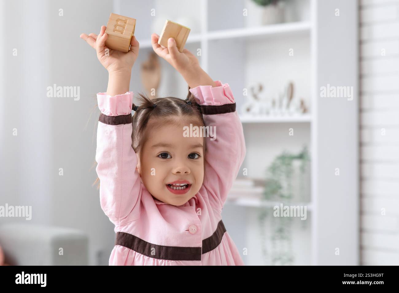 Cute little girl holding cubes with letters at home Stock Photo - Alamy
