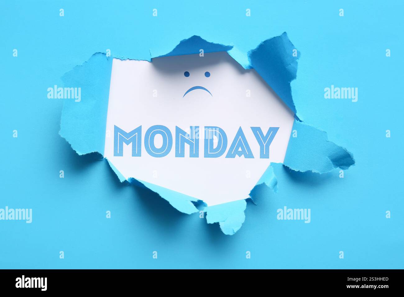 Paper sheet with word MONDAY and sad face visible through torn hole ...