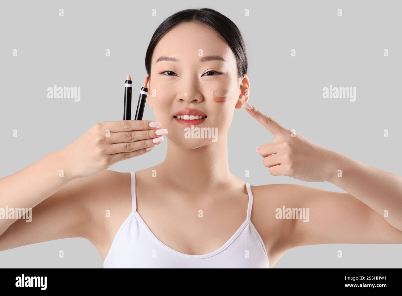 Beautiful Asian woman with different tonal foundations on grey ...
