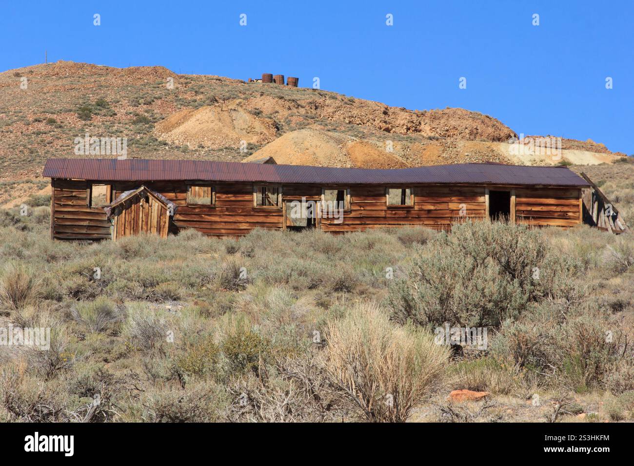 A large, old wooden building sits on a hillside. The building is ...