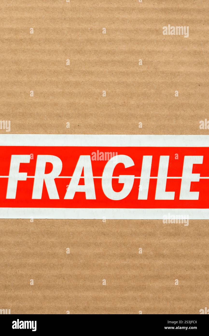 Fragile tape stuck across a cardboard box. Business and industrial packing background concept ...