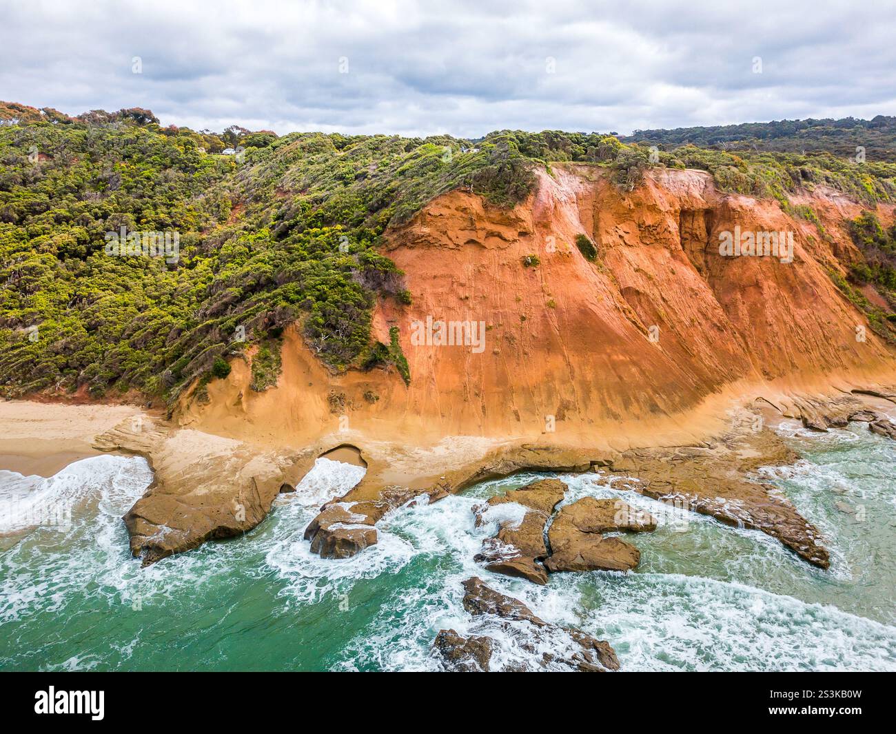 Aerial view of waves breaking on rock ledges below high cliffs at ...