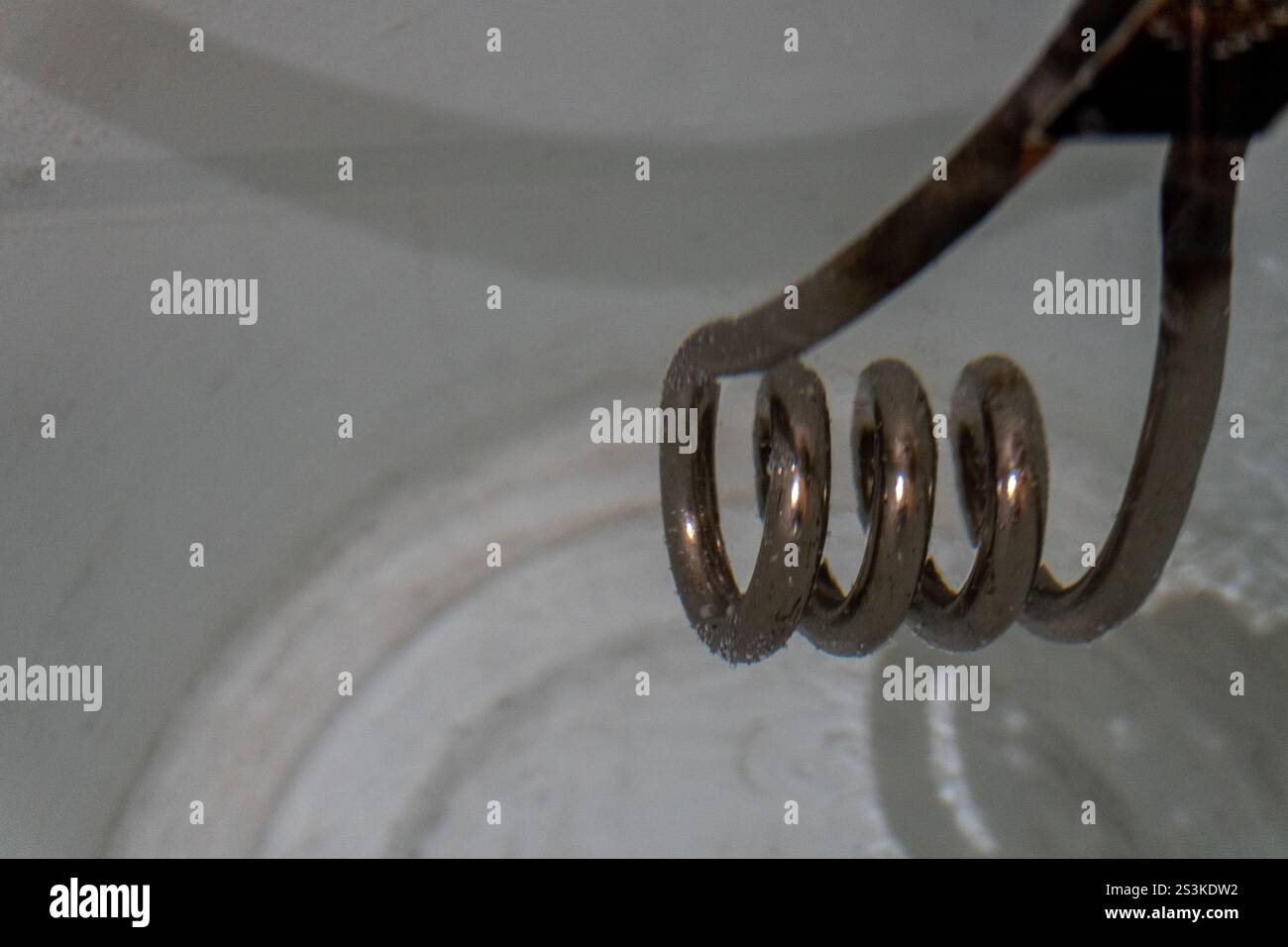 A heating rod submerged in a bucket of water, radiating visible heat ...