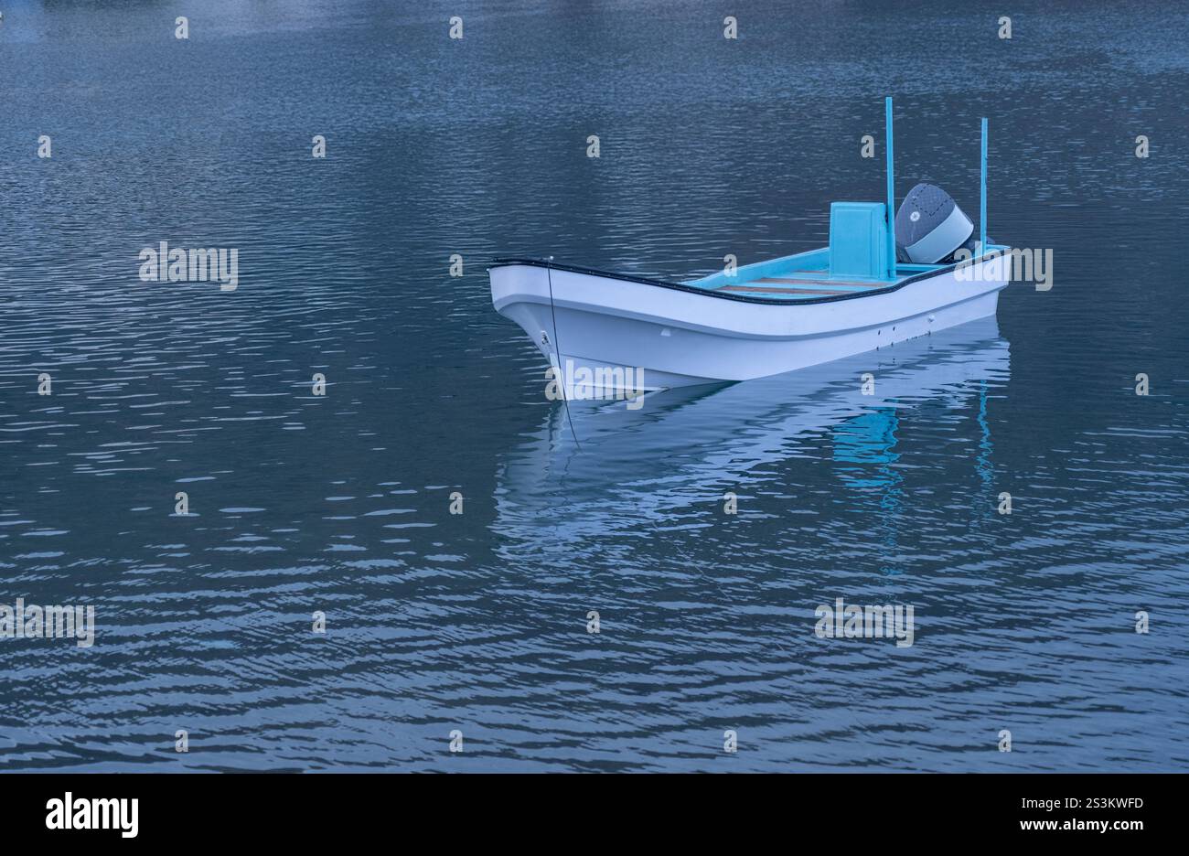 A serene white and blue Omani fishing boat floating on calm waters ...