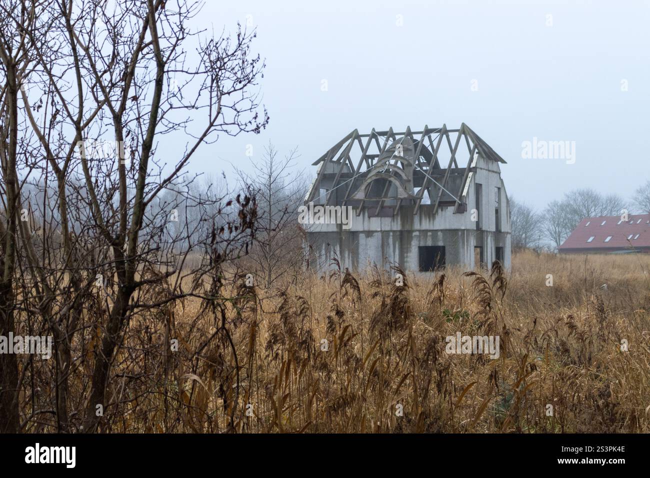 Abandoned, incomplete house structure in a foggy field surrounded by ...