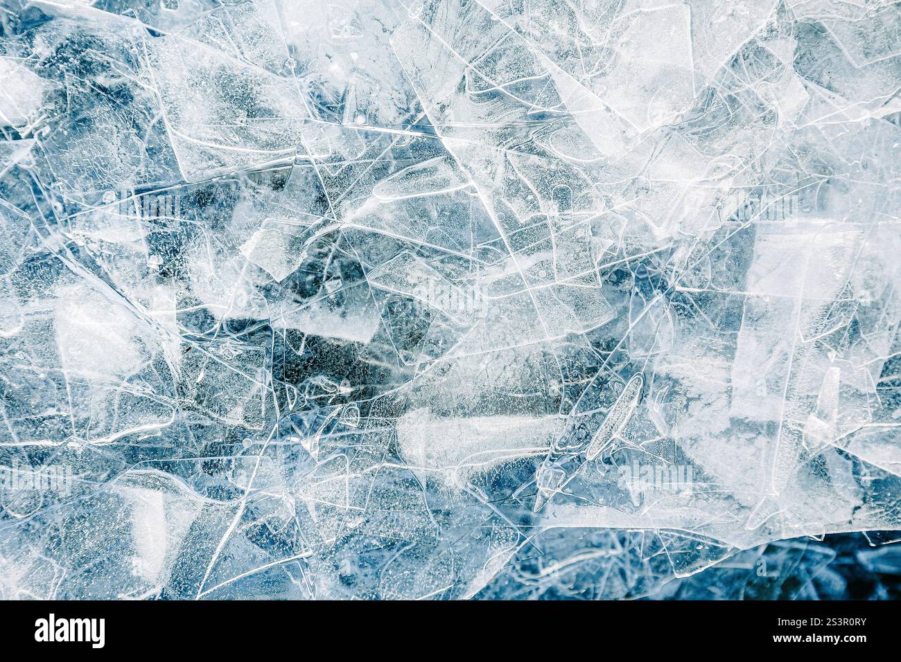 Close-up texture of shattered ice in varying shades of blue and white. The image captures the ...