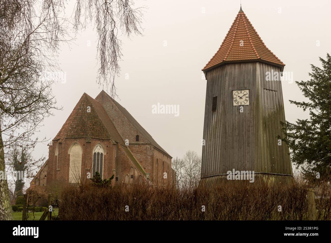 An old church and its wooden bell tower stand side by side on a foggy ...