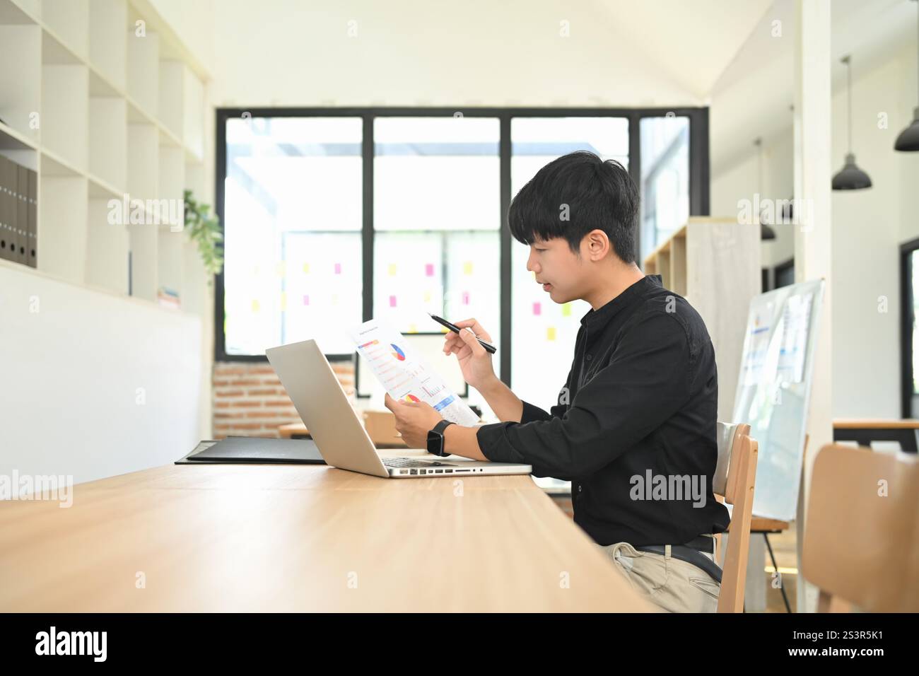 Young businessman reviewing report with charts and graphs while working ...