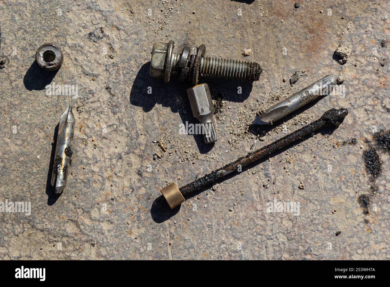 A collection of metal tools and fasteners is laid out on a rugged ...