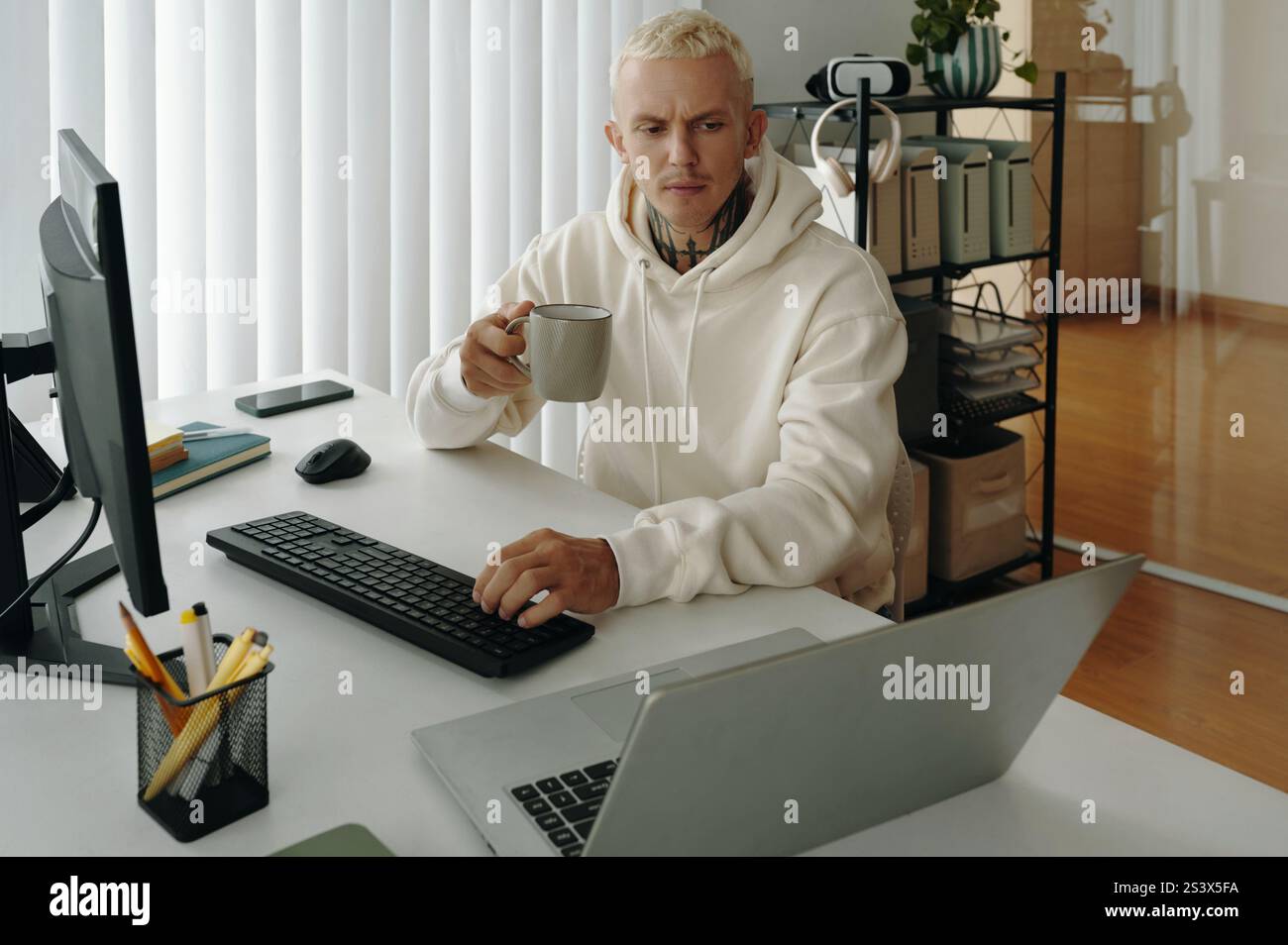 Programmer sitting in front of desktop pc, drinking coffee and ...