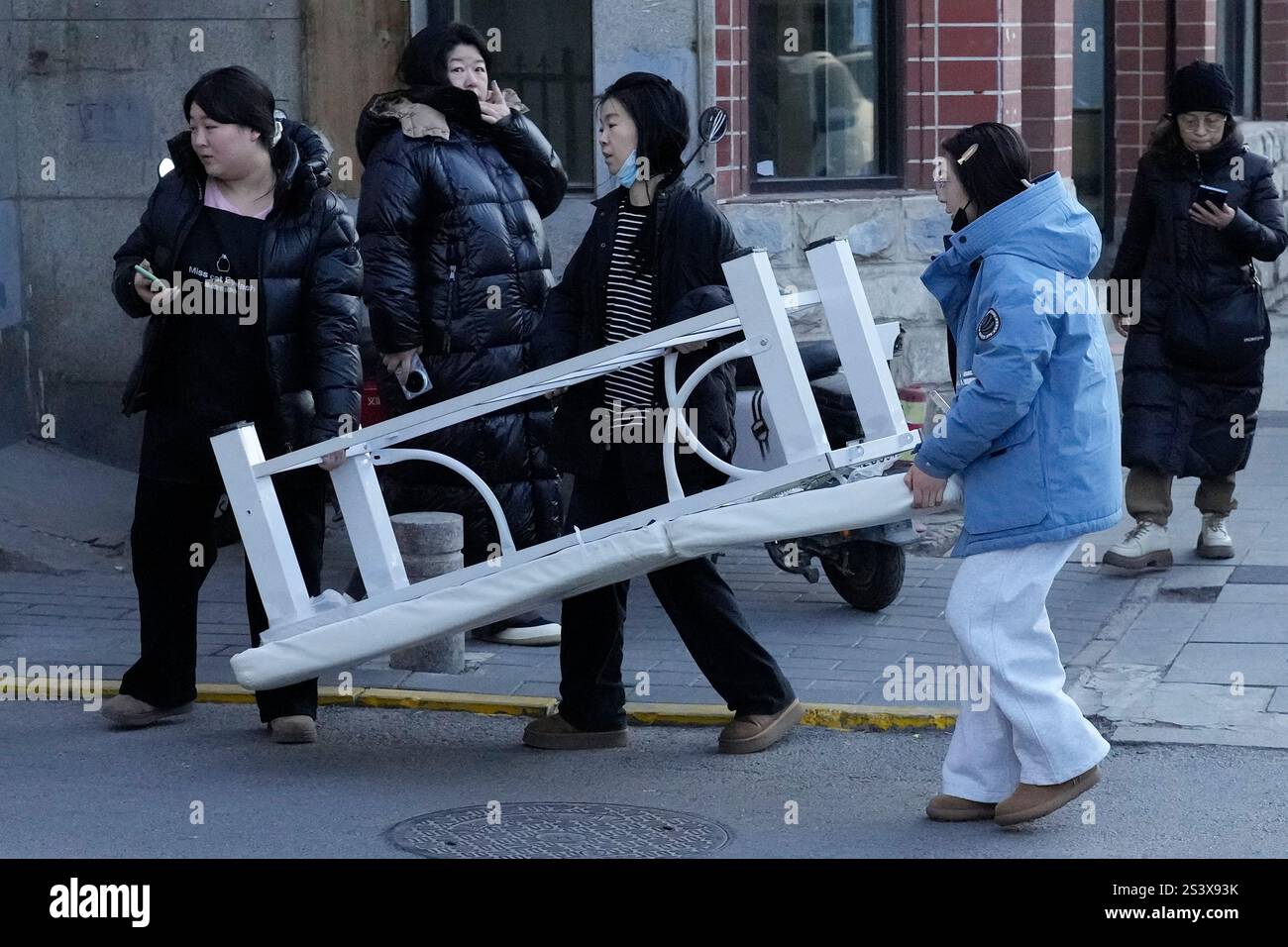 Women carry a table along a street in Beijing, China on Friday, Jan. 10 ...