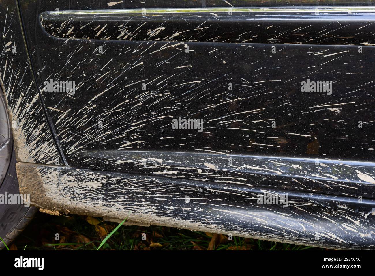 A dirty car with mud splattered on the side shows signs of an ...