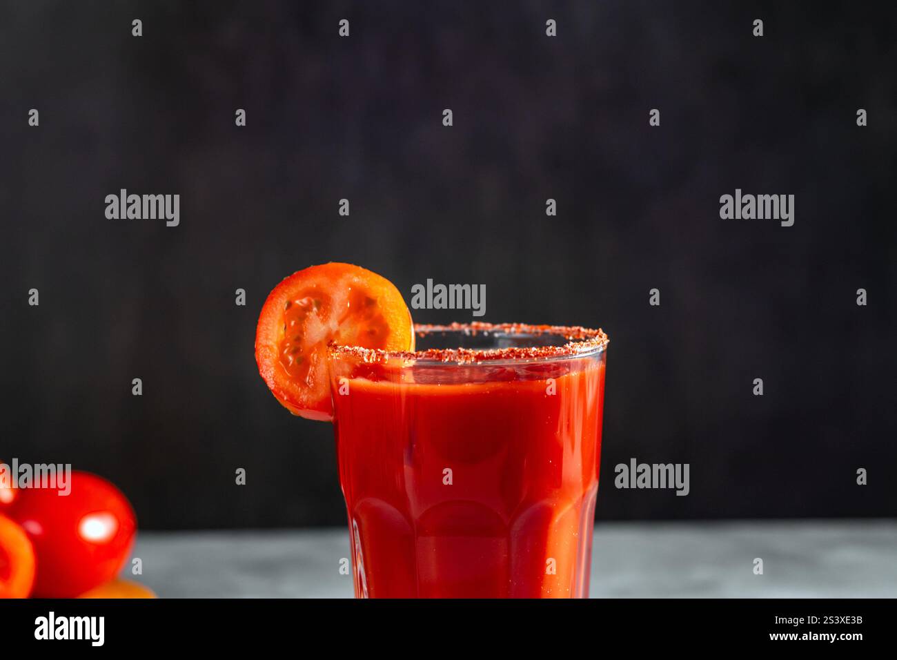 Vegetable shaken cocktail in glass on dark grey background. Red tomato ...