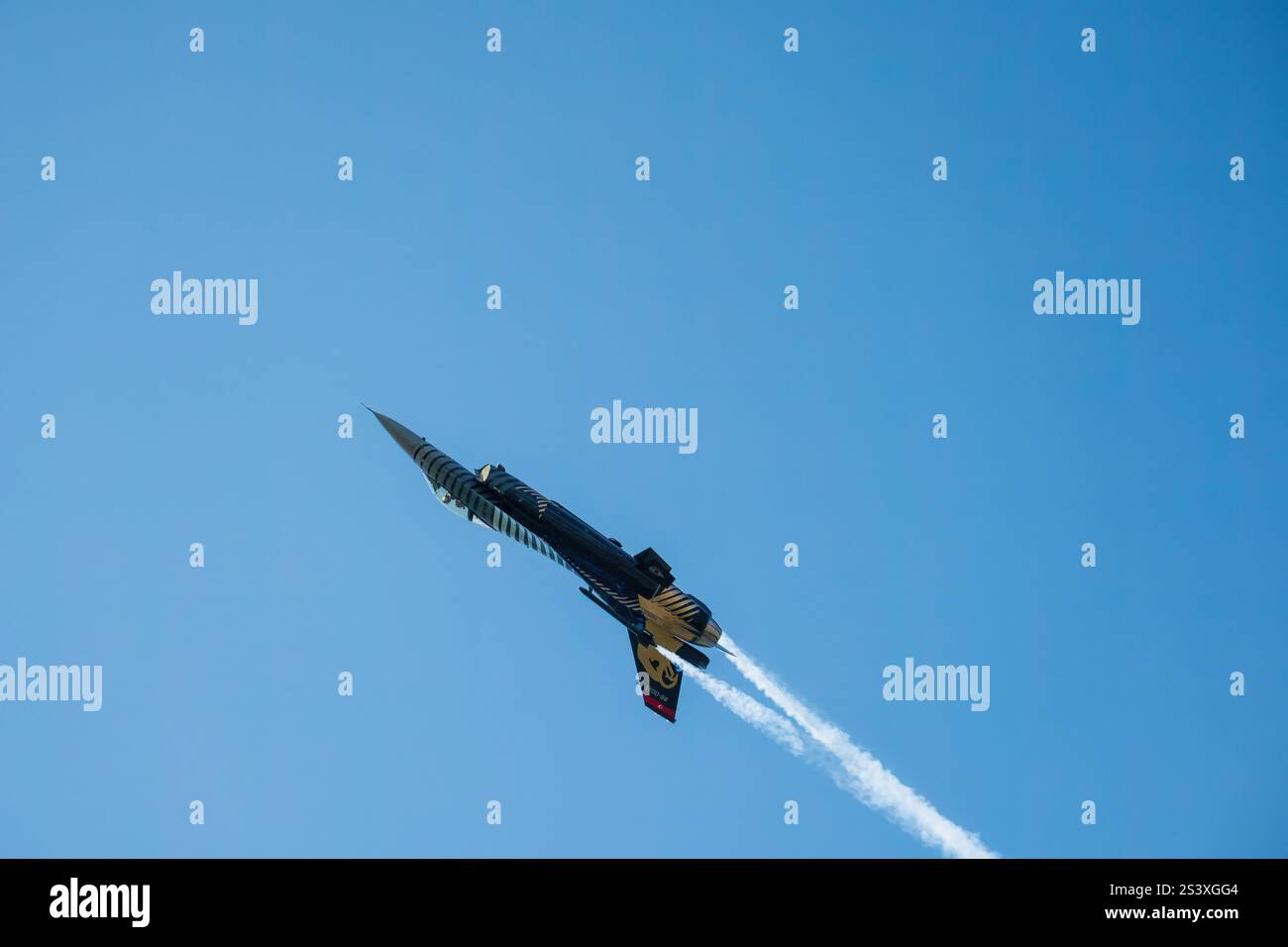 F-16 fighter jet performing a daring vertical climb against a backdrop ...