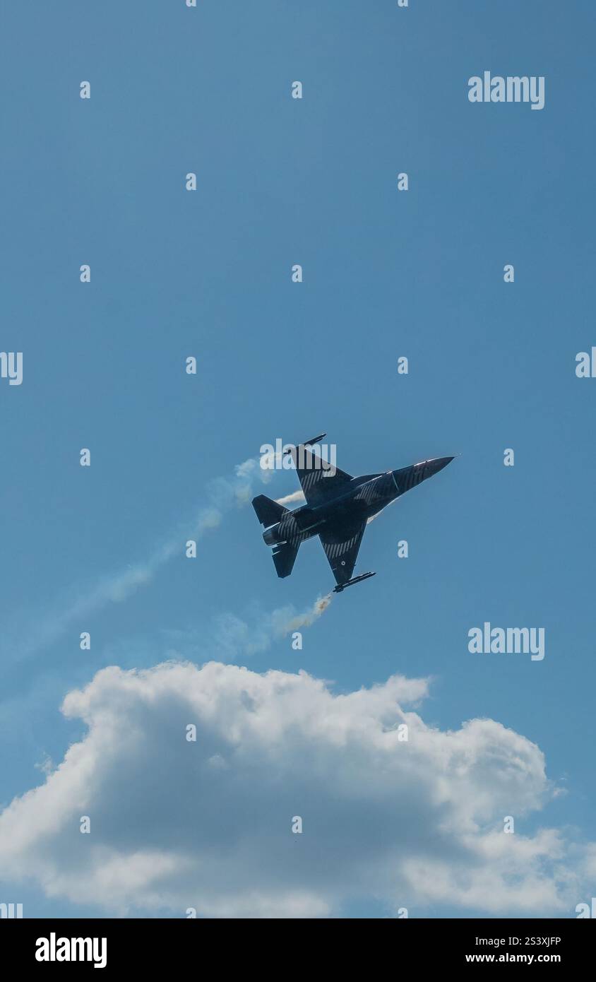 F-16 fighter jet performing an acrobatic maneuver against a backdrop of ...