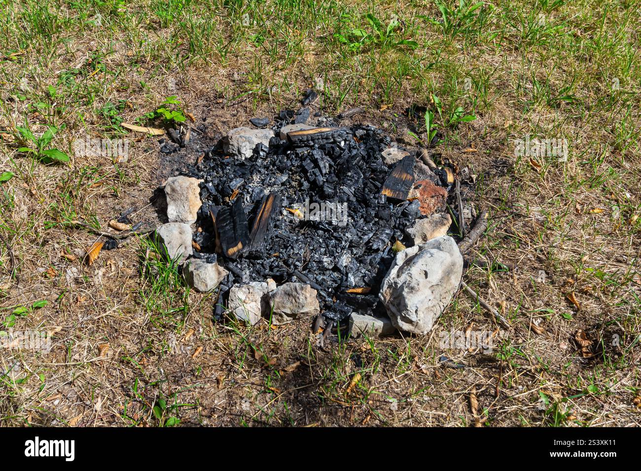 Charred remains of a fire pit are visible in a grassy area, surrounded ...