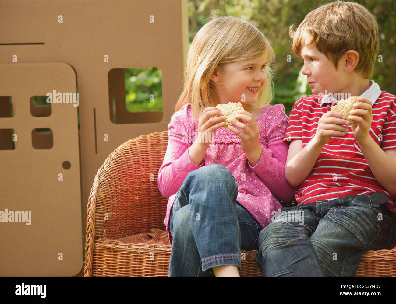 Boy and girl eating biscuits looking at each other Stock Photo - Alamy