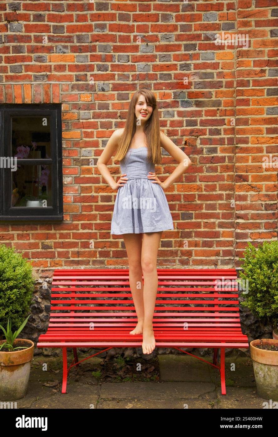 Teenage Girl Standing on Red Bench Stock Photo - Alamy