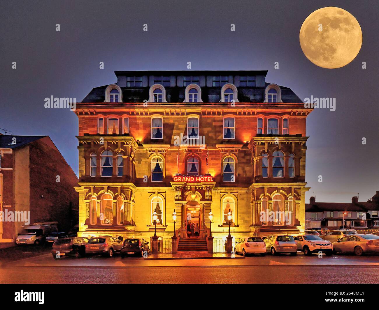 Grand Hotel Tynemouth lit up at night with a full moon as background ...