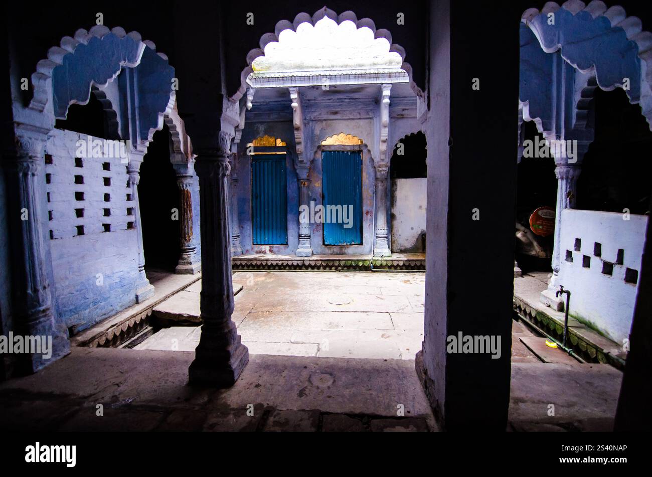 Visitors admire the detailed arches and vibrant blue doors of an old ...