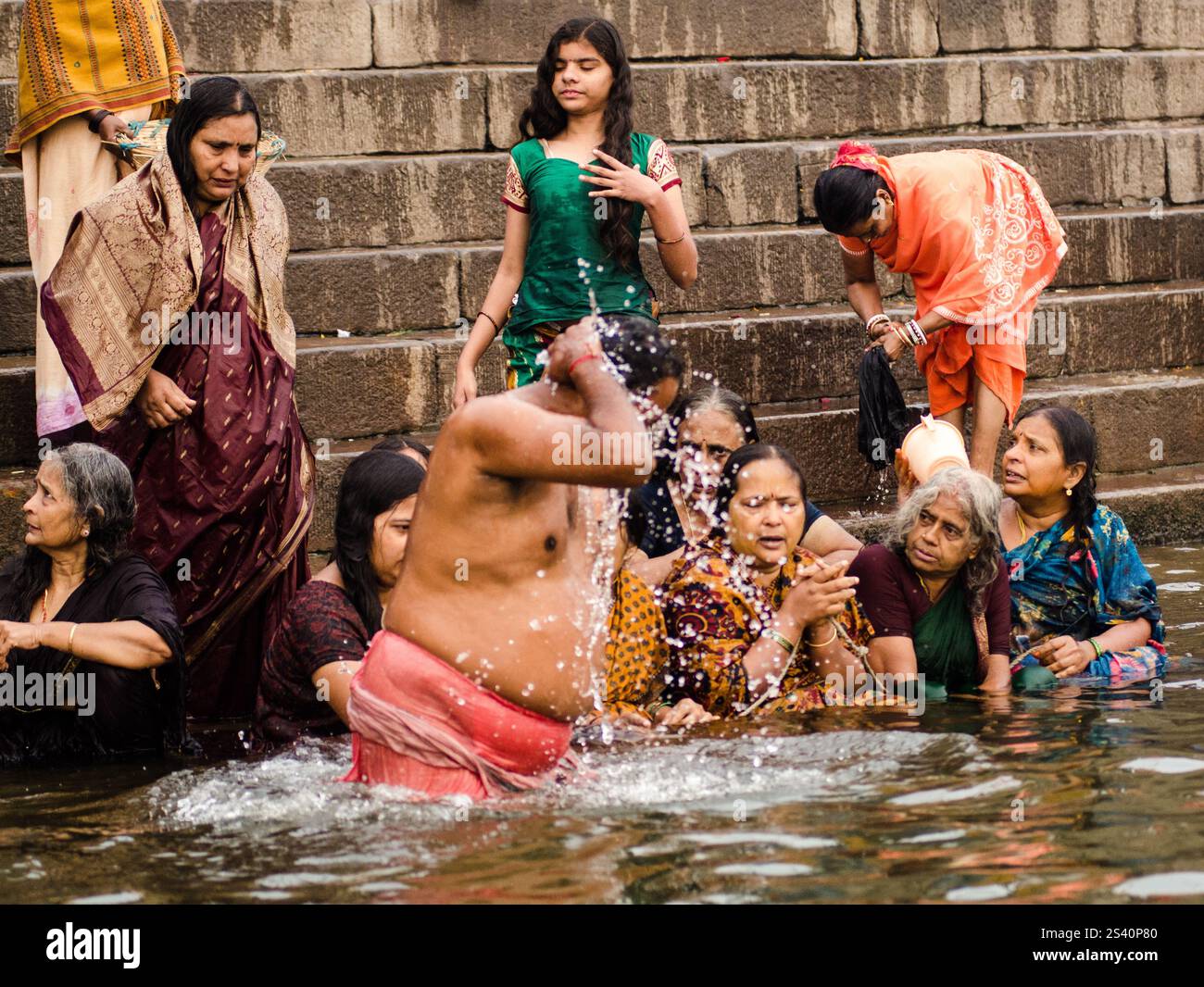 Devotees engage in spiritual cleansing in the Ganges River, surrounded ...