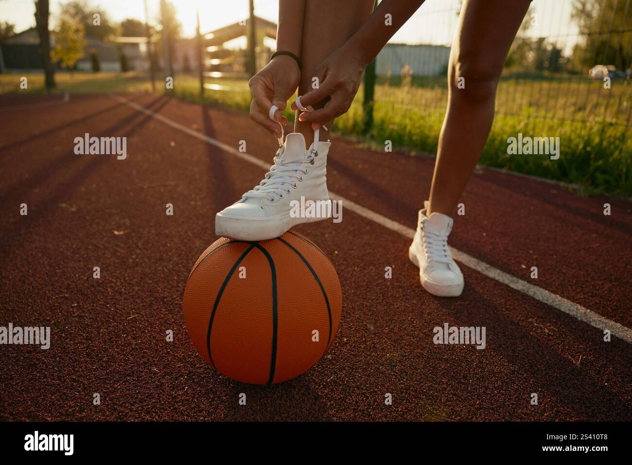Female basketball player tying shoelaces putting foot on ball Stock ...
