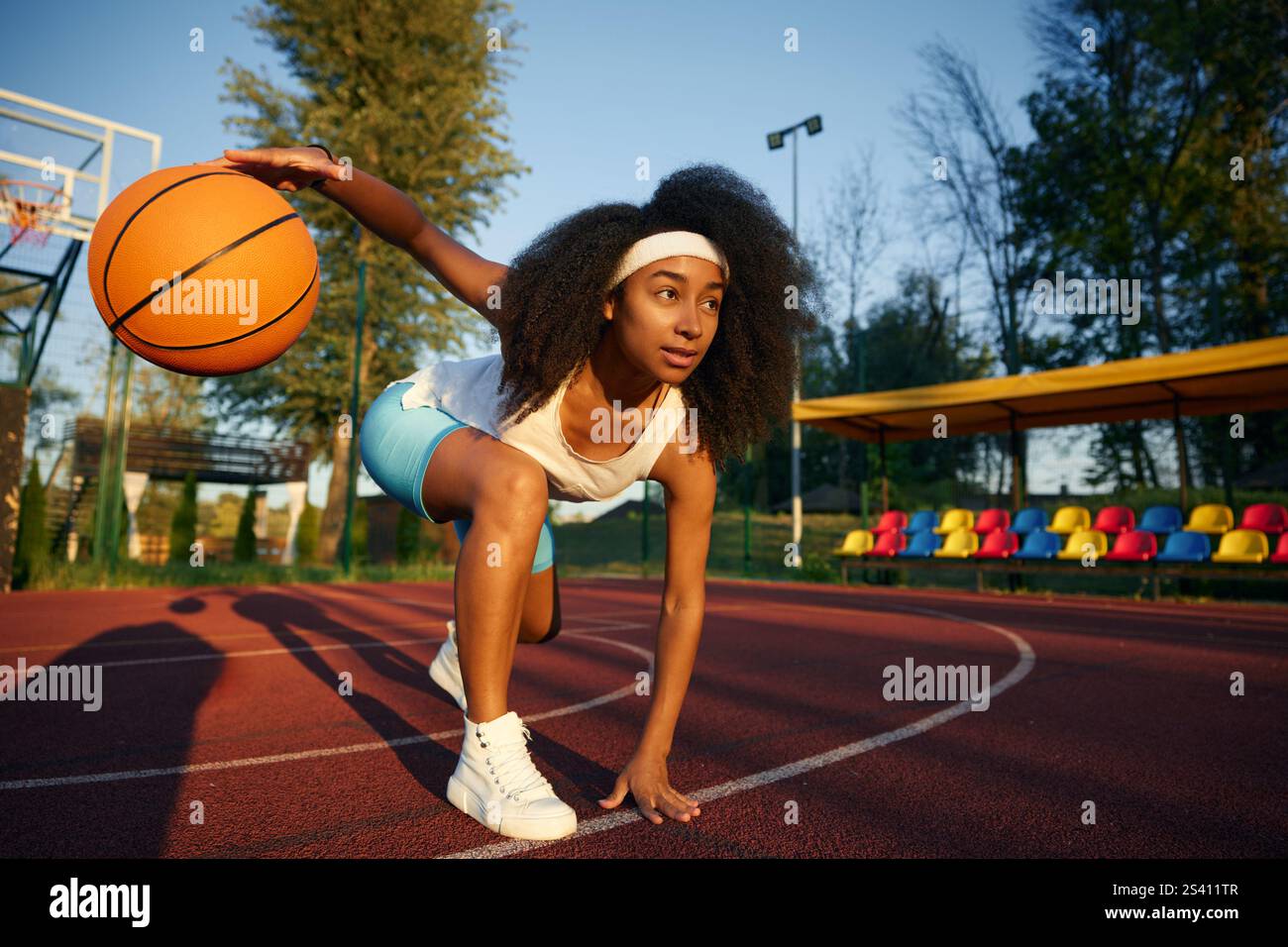 Young female basketball player in low start position dribbling ball ...