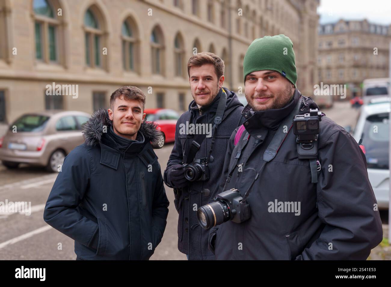 Three men stand on an urban street with photography gear, highlighting ...