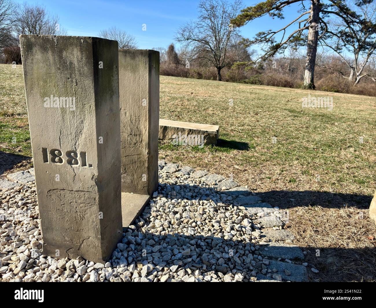 Stone monument engraved with "1881" in grassy field under a clear sky ...
