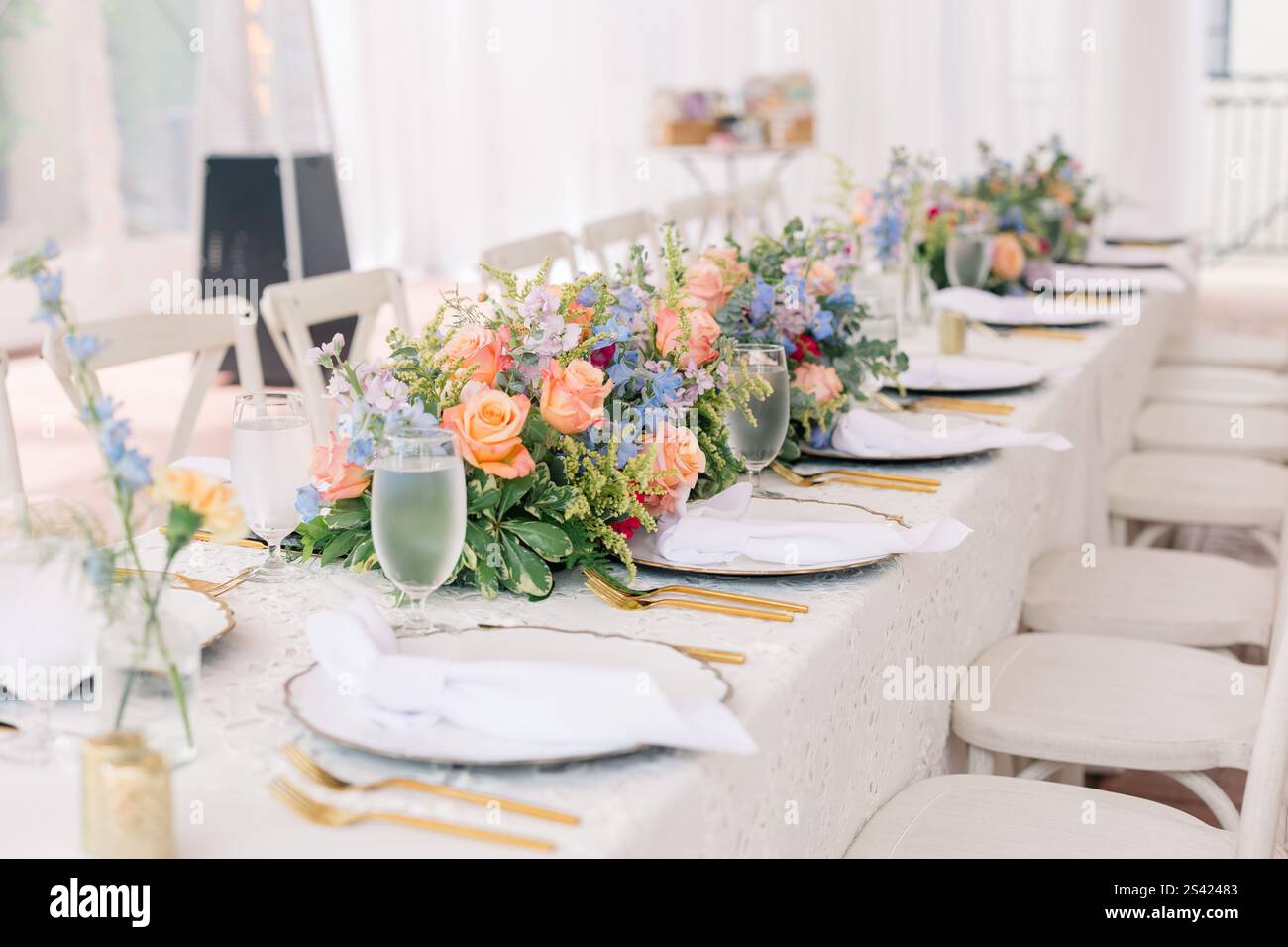 Elegant long table setup with floral centerpieces and gold accents ...
