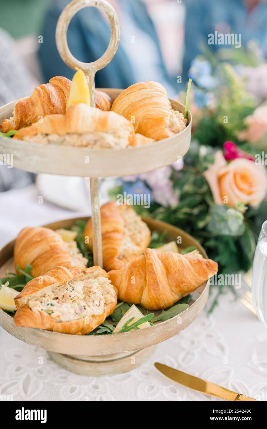 Tiered serving stand with croissant sandwiches and fresh garnish Stock ...