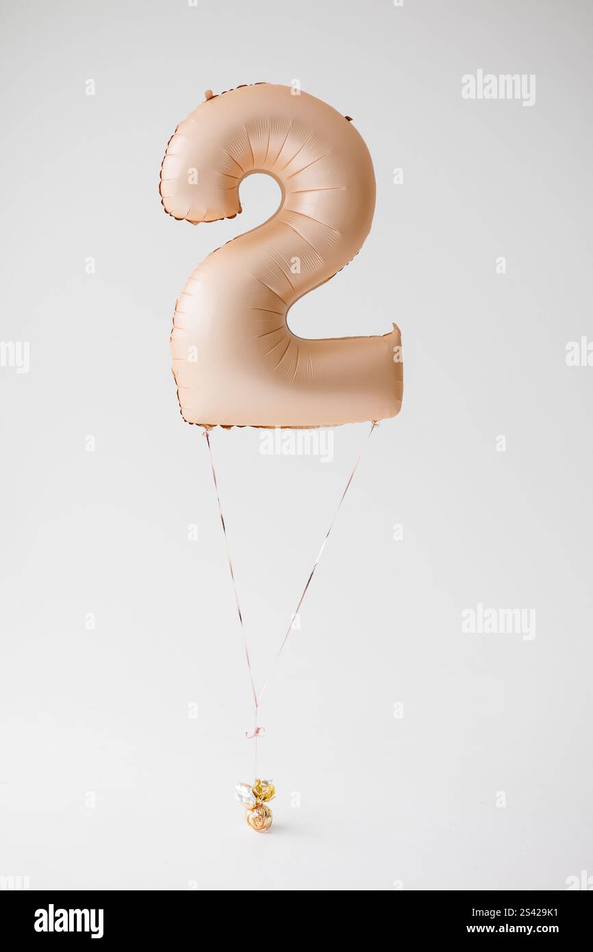 Soft pink-peach number two helium foil balloon for 2 years on white ...