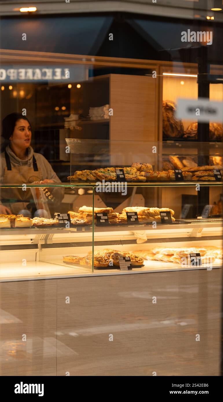 Bakery display showcases a variety of pastries while the baker prepares ...